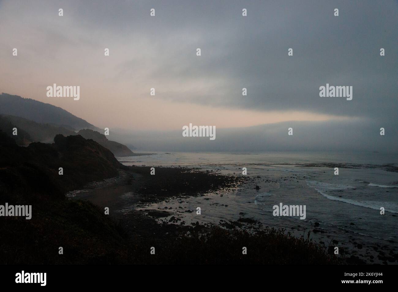 Thick mist coming from the ocean. Seacoast view with cliffs and rocks ...
