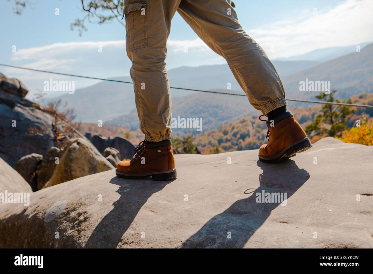 hiking concept men legs in boots on the rock Stock Photo - Alamy