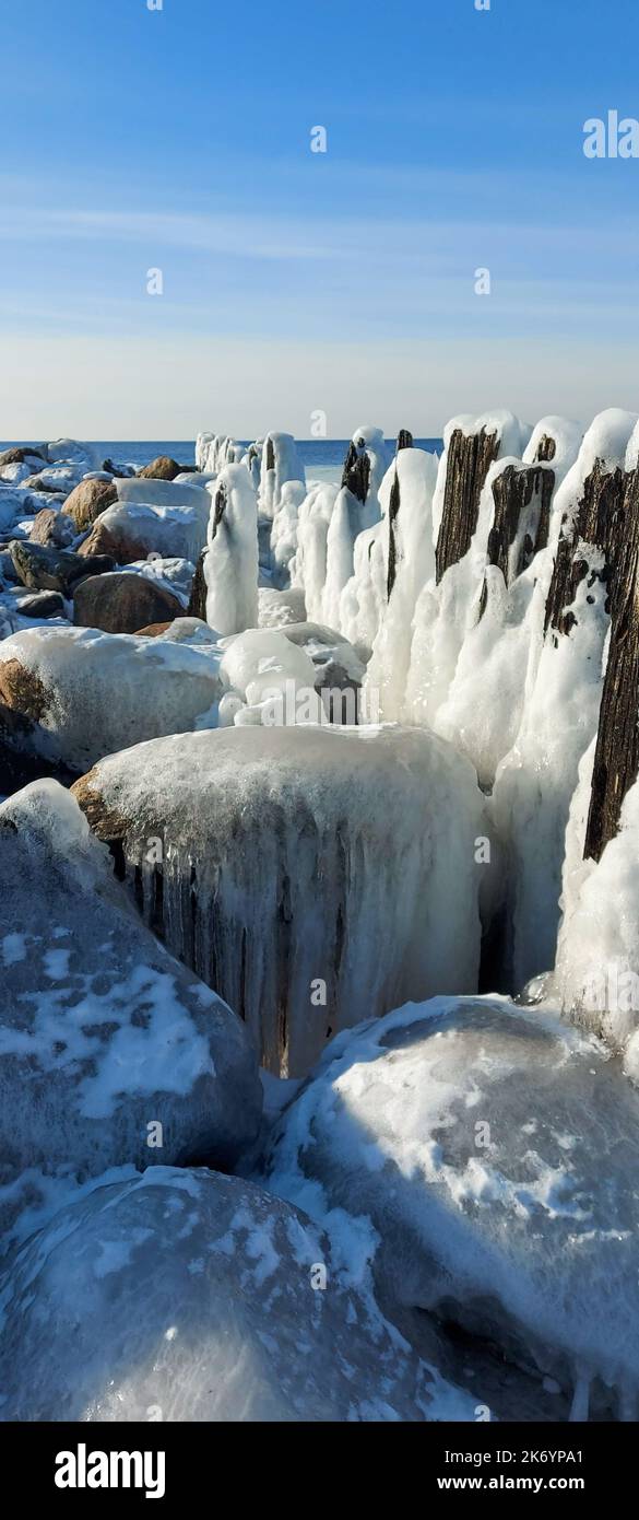 Pier poles and rocks covered with snow on a sunny winter day with some ...
