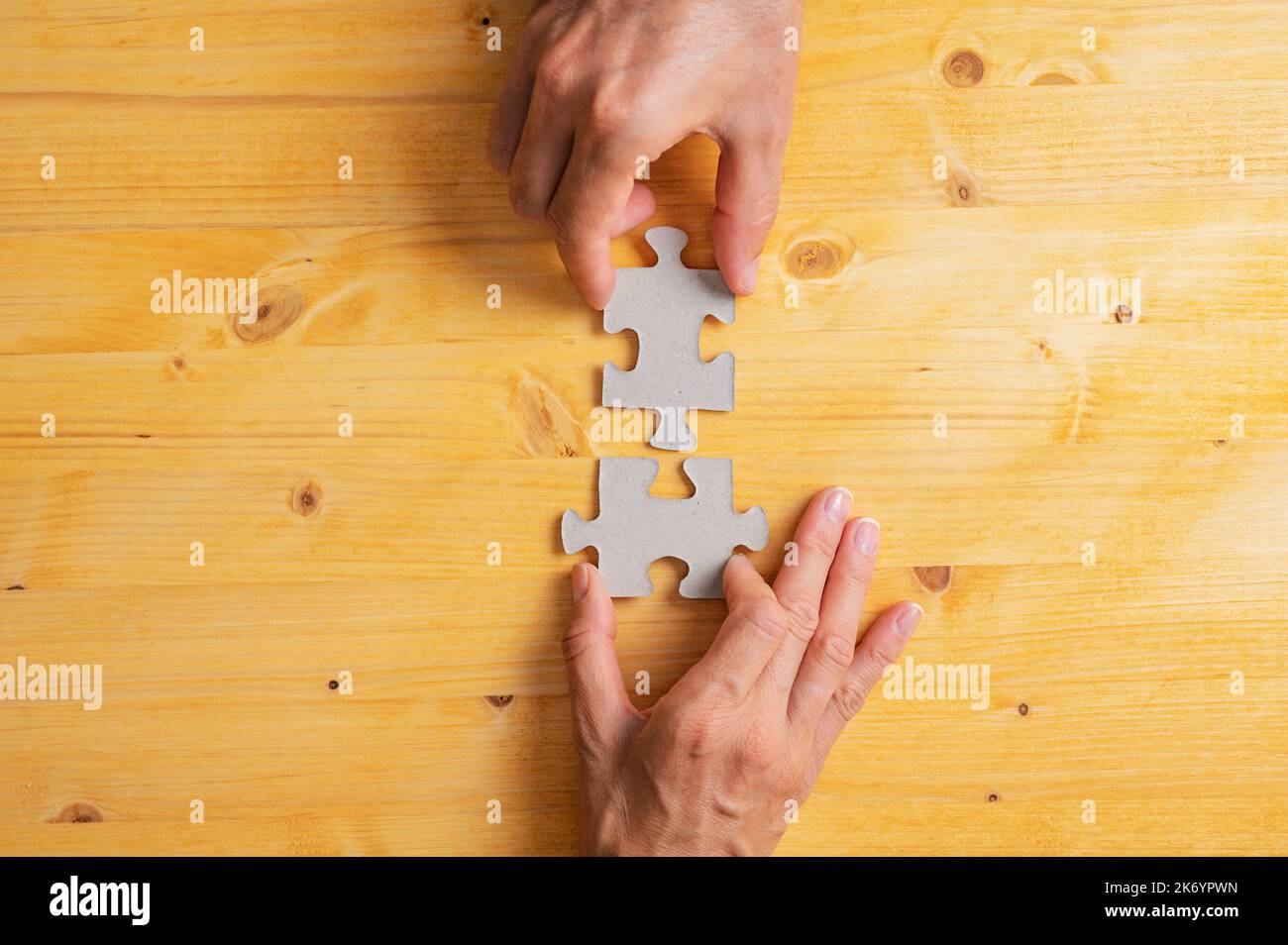 Male and female hand joining two matching puzzle pieces over yellow ...