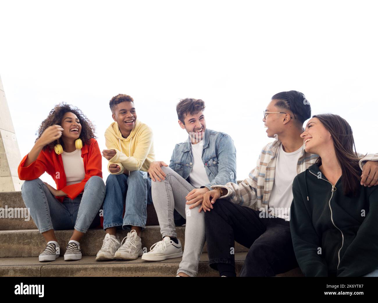 Group of diverse young friends laughing and talking to each other ...
