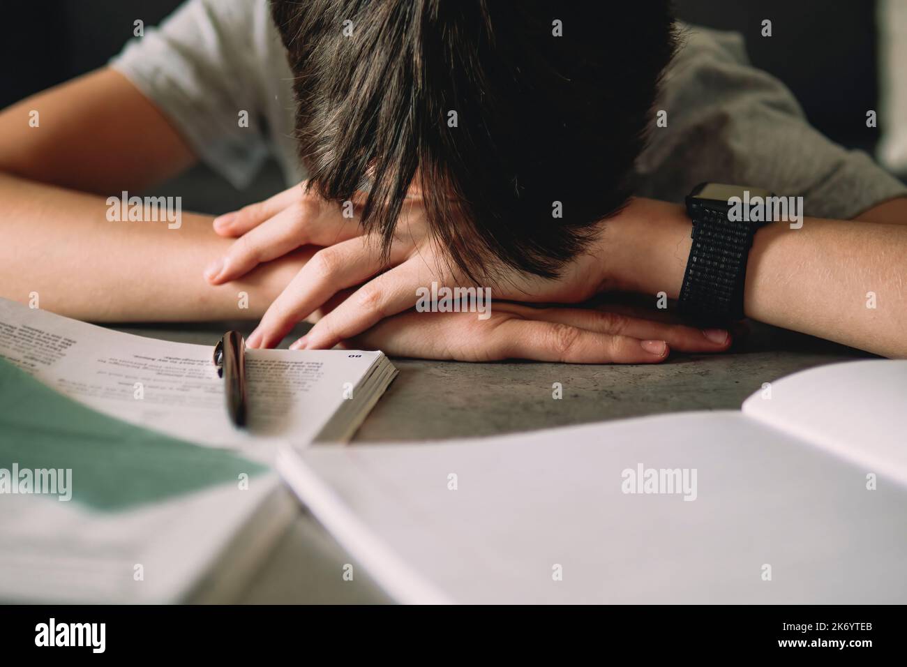 Tired disappointed teenage boy lowering his head sitting among pile of ...