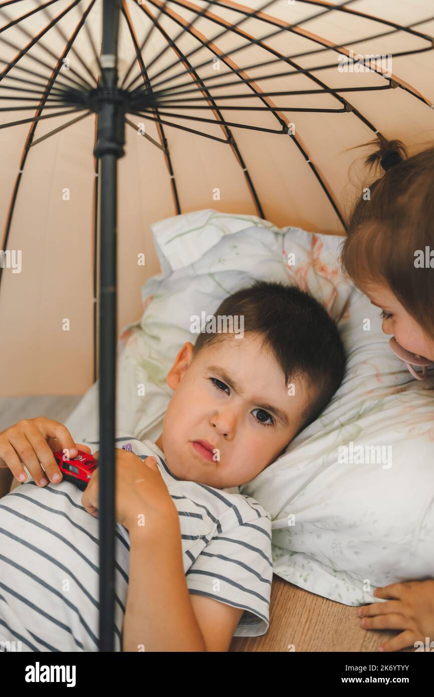 Boy glaring at the camera while lying down in the room under an ...