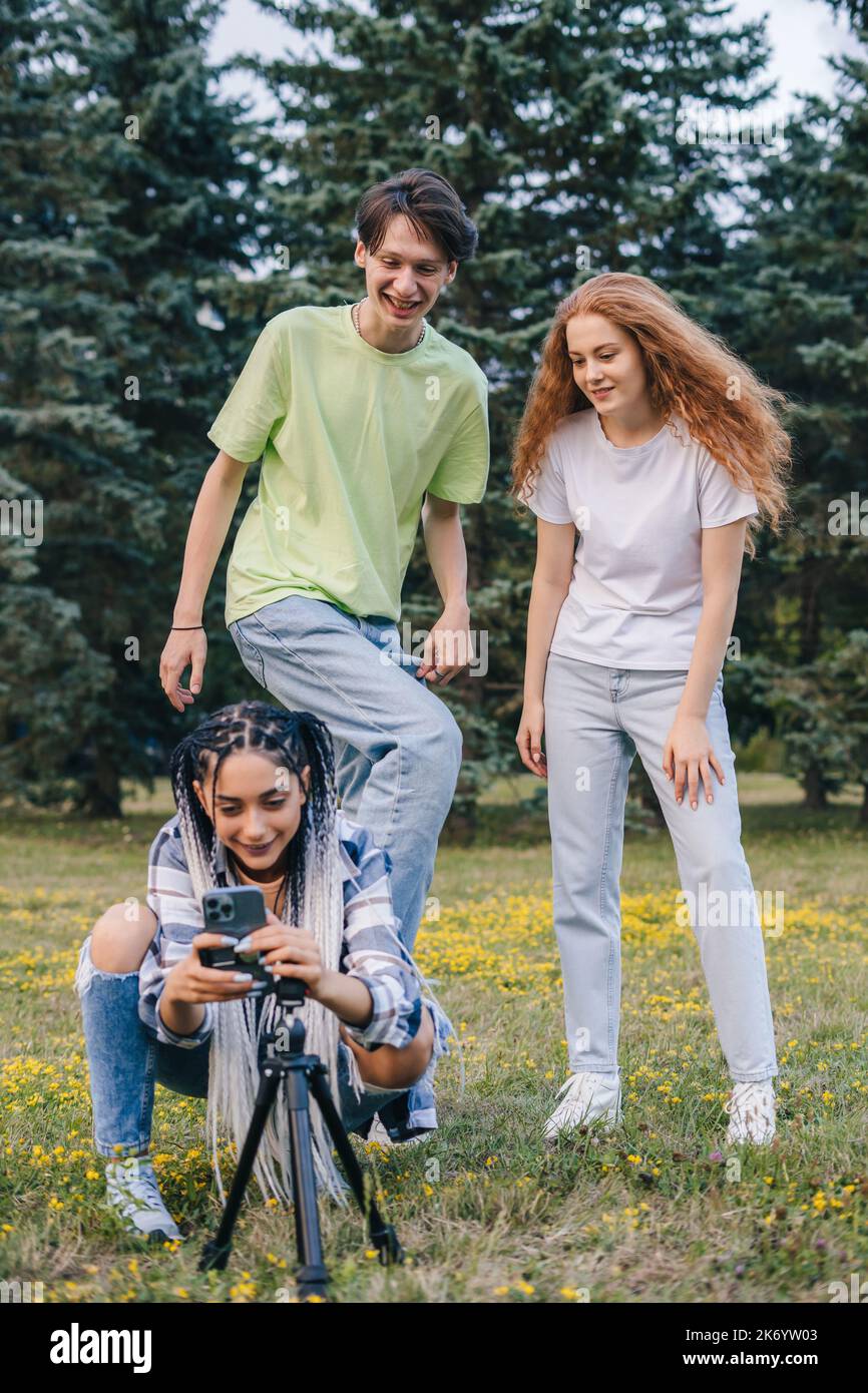 Cheerful three friends dancing in the green park, filming video using ...