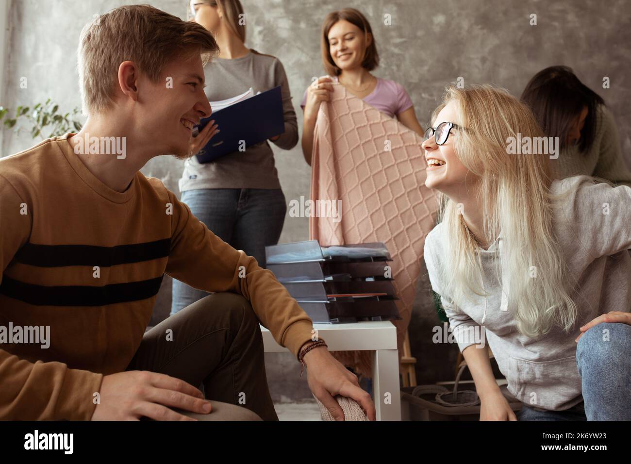 Positive smiling, glad students sitting on the floor, packing luggage ...