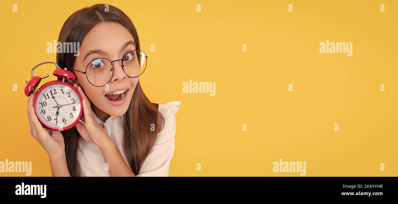 amazed child in school uniform and glasses listen alarm clock ringing ...