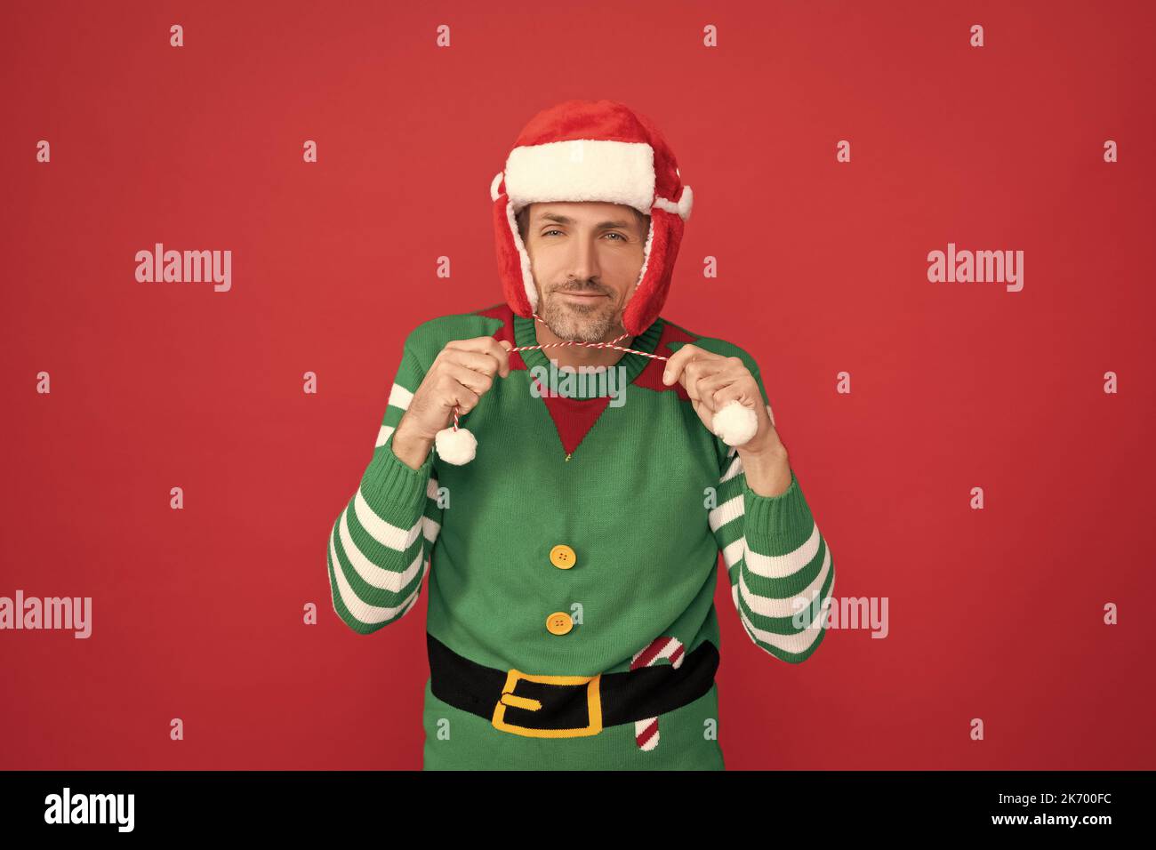 funny man in elf costume. xmas guy in santa claus hat on red background ...