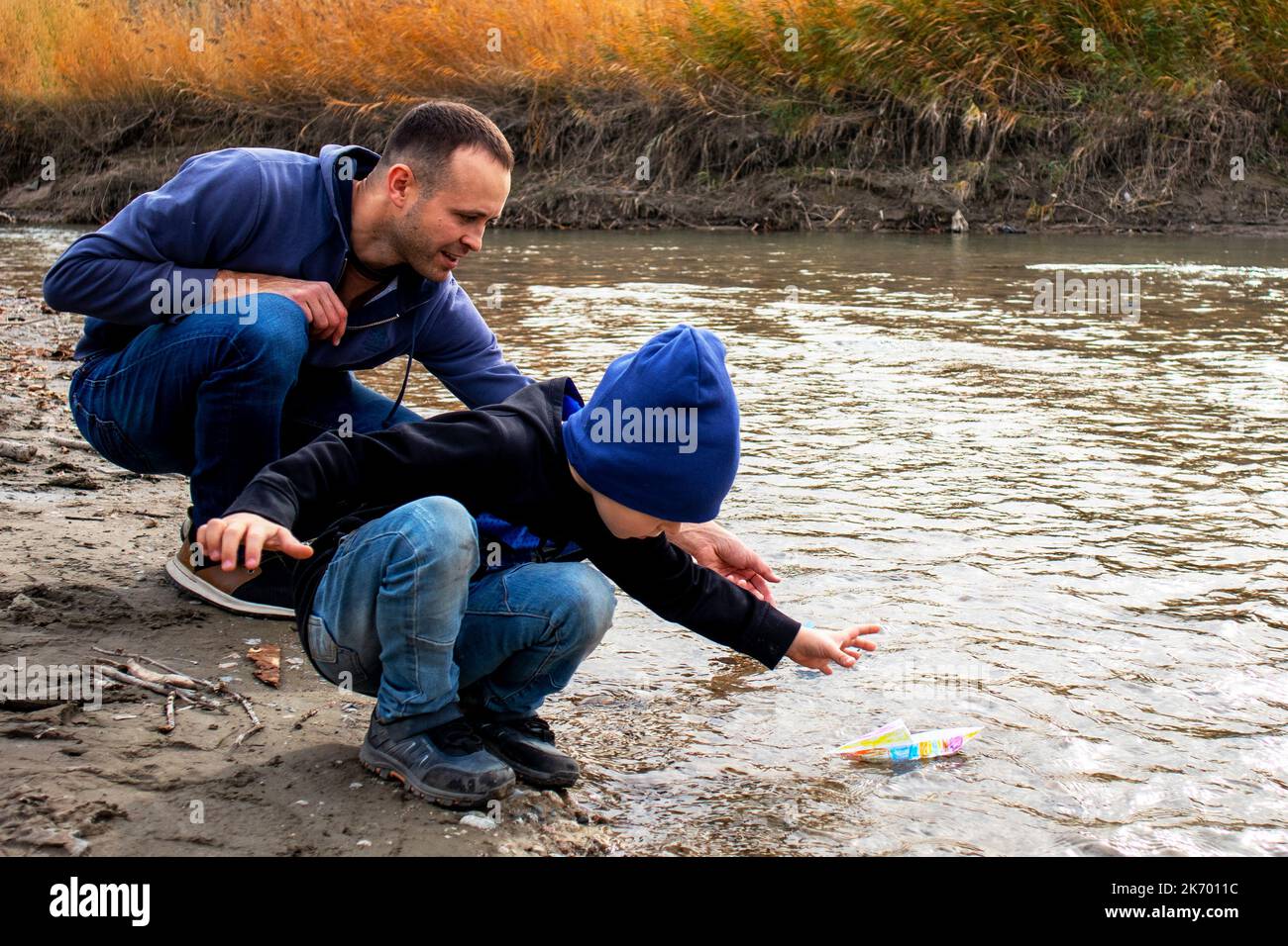 a little boy and his dad launch a paper boat. origami boat Stock Photo ...