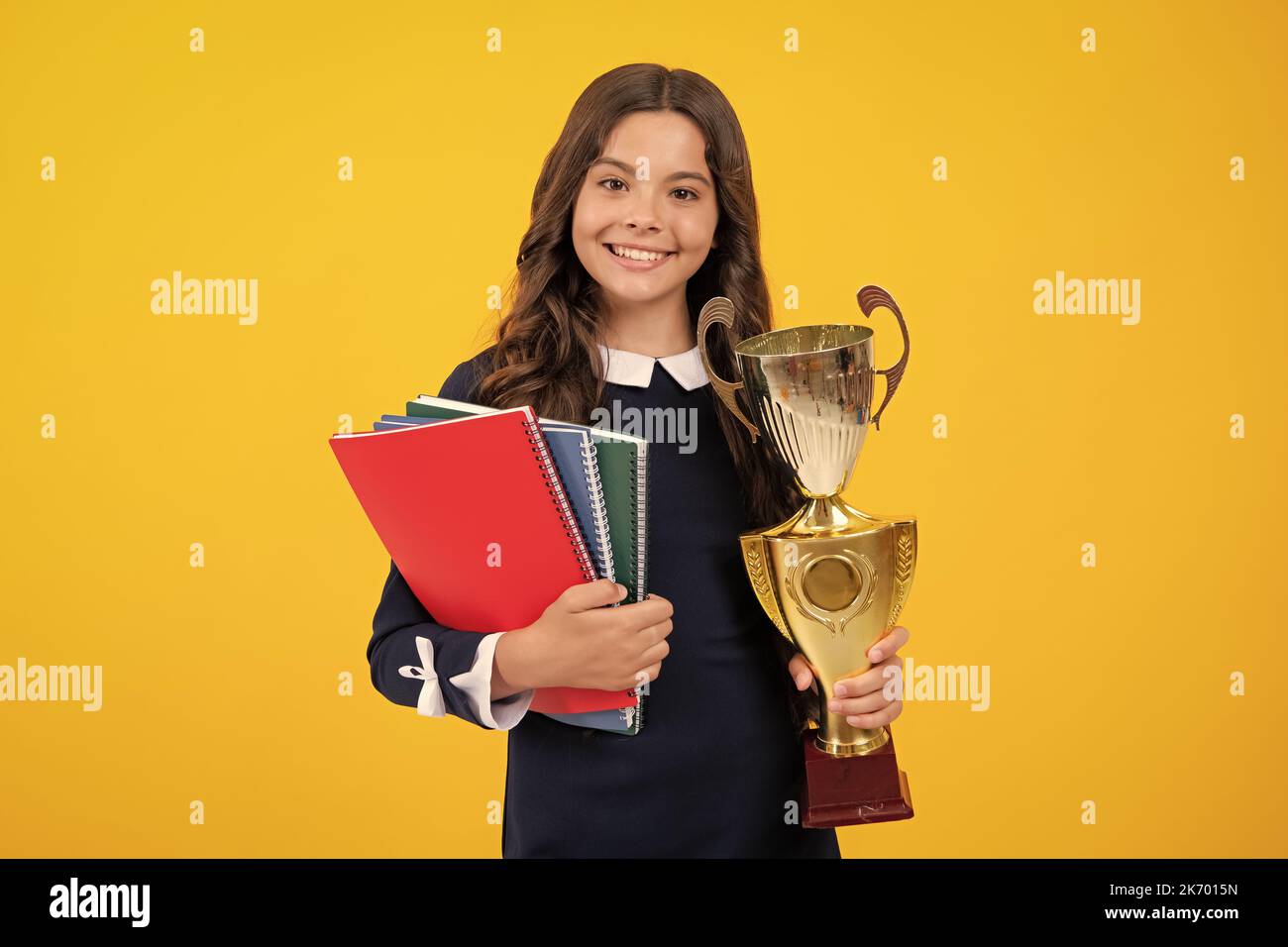 Schoolgirl in school uniform celebrating victory with trophy. Teen ...
