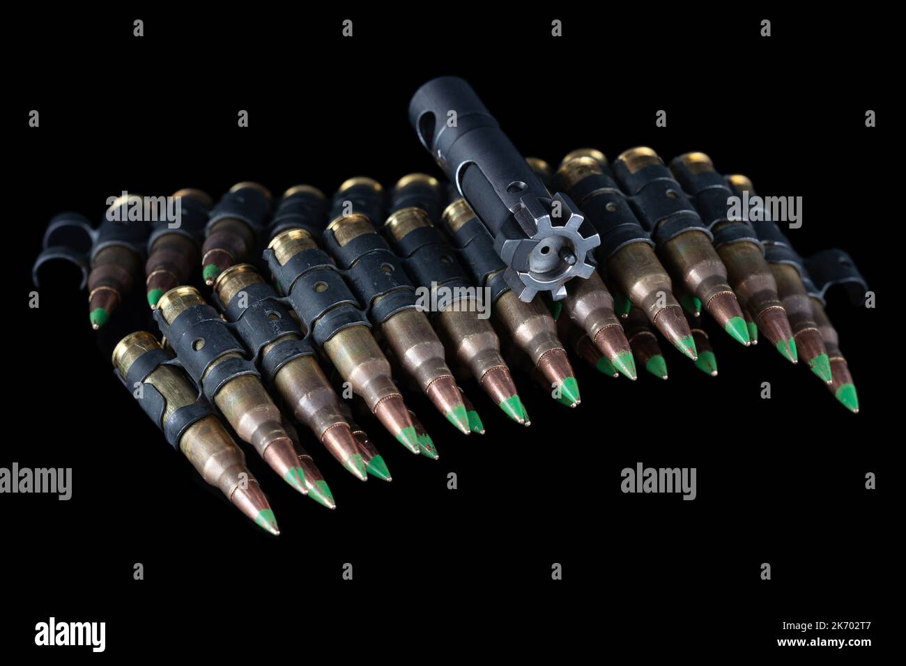 5.56mm NATO ammunition belt with assault rifle bolt on black background ...