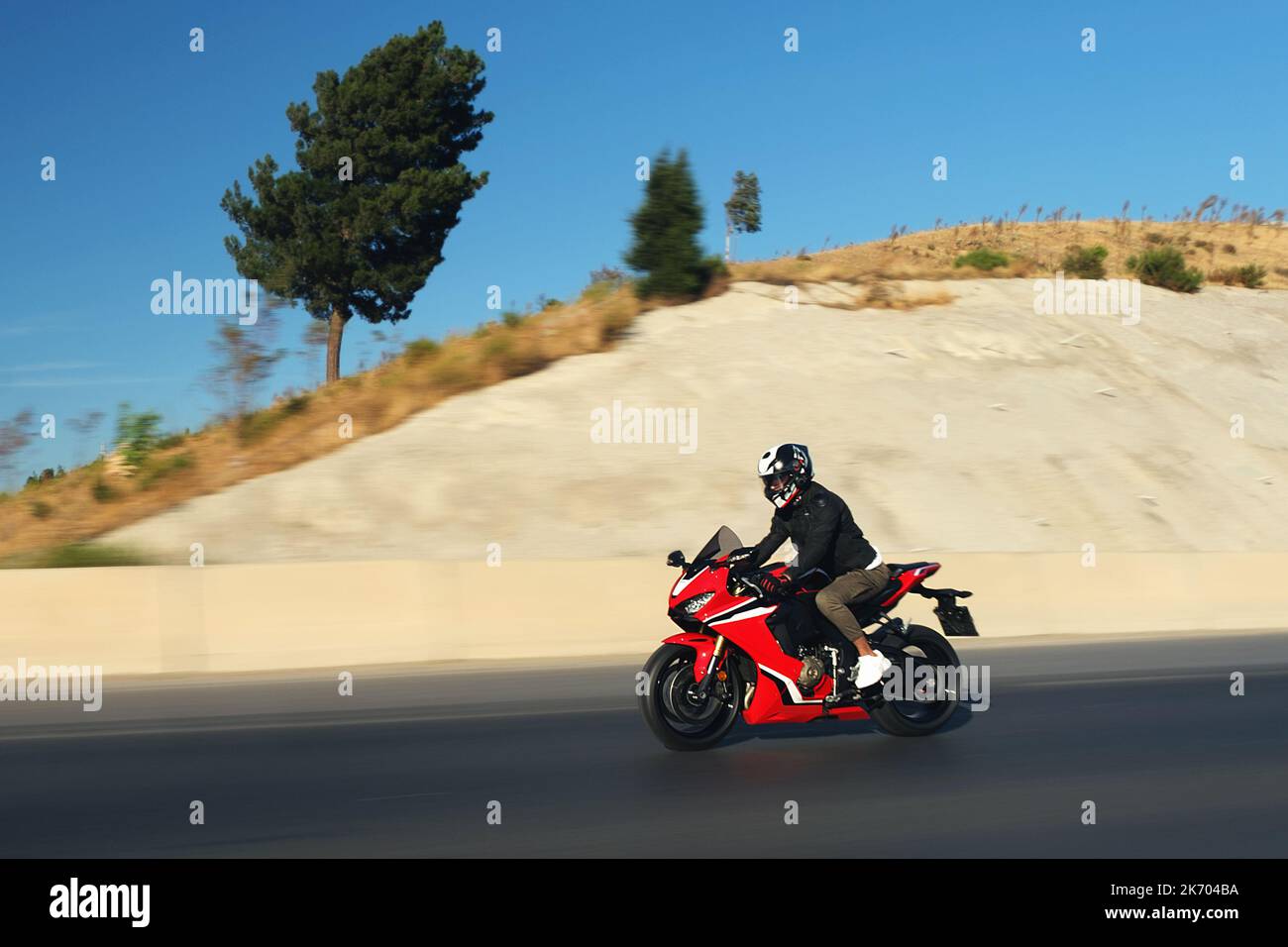 Side view of a motorcycle rider riding red race motorcycle on the ...