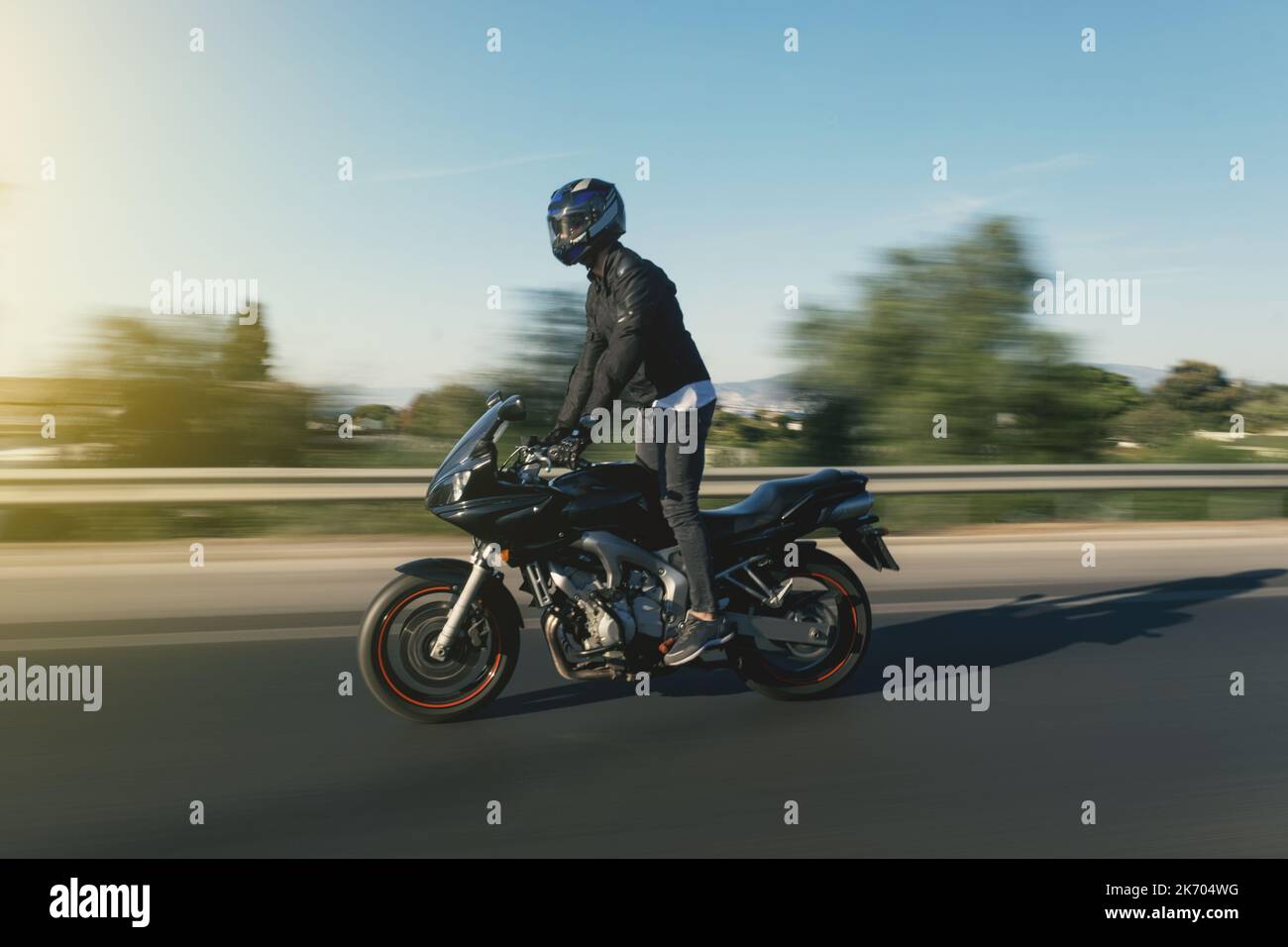 Side view of a motorcycle rider riding race motorcycle on foot on the ...
