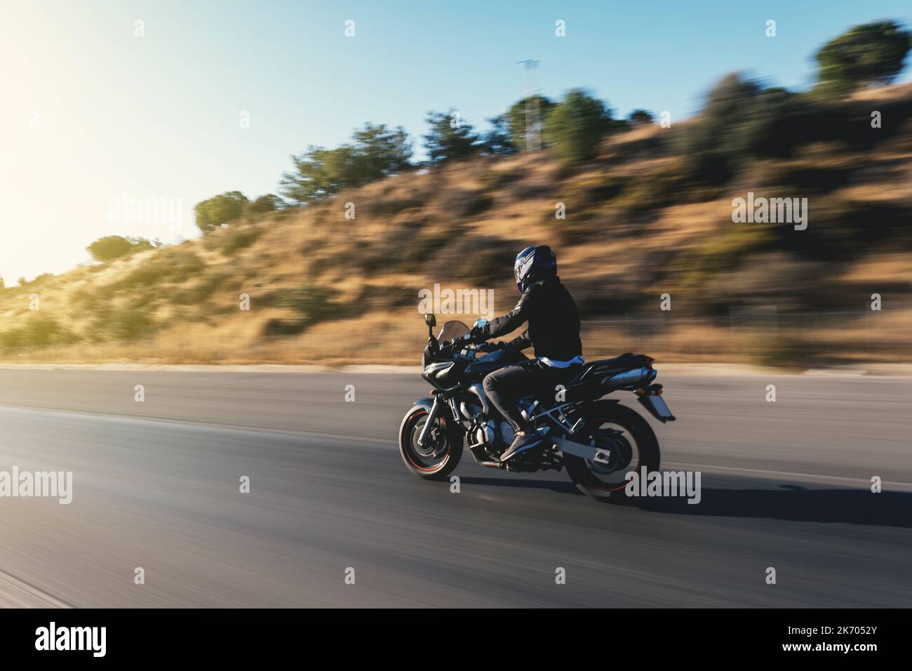 Side view of a motorcycle rider riding on the highway with motion blur ...