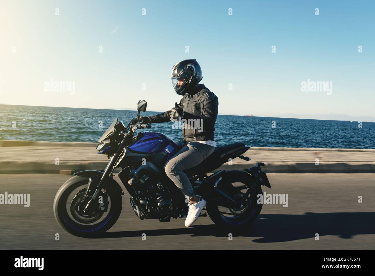 Side view of a motorcycle rider riding race motorcycle on a sea ...