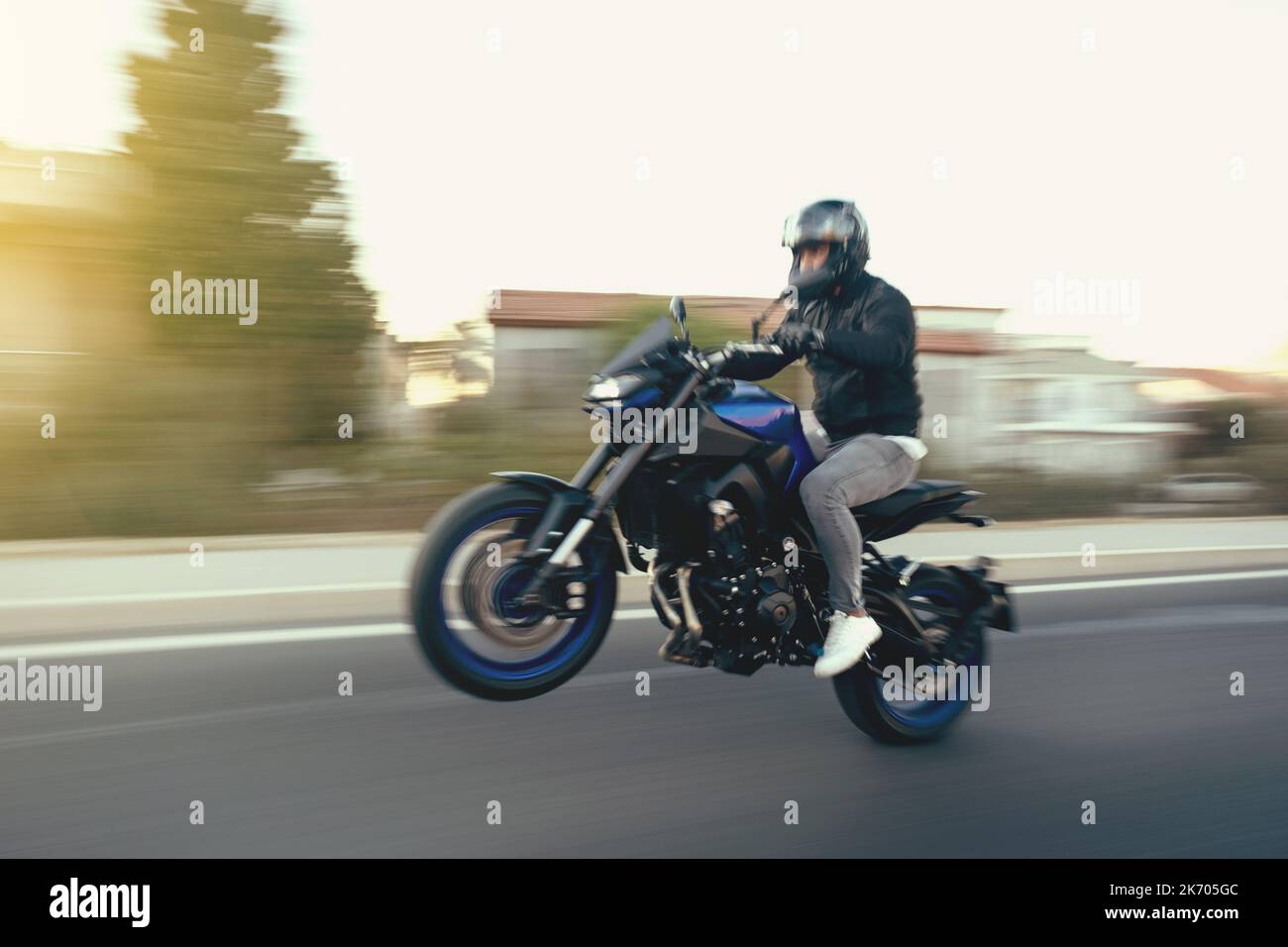 Side view of a motorcycle rider riding race motorcycle on a wheelie the ...