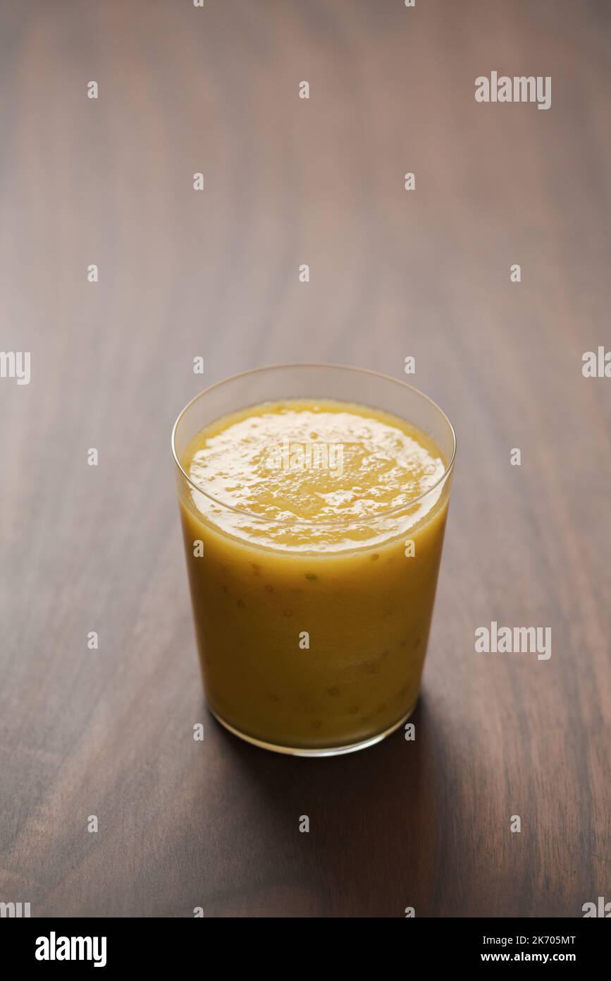 Mango lulo smoothie on walnut wood table with copy space, shallow focus ...