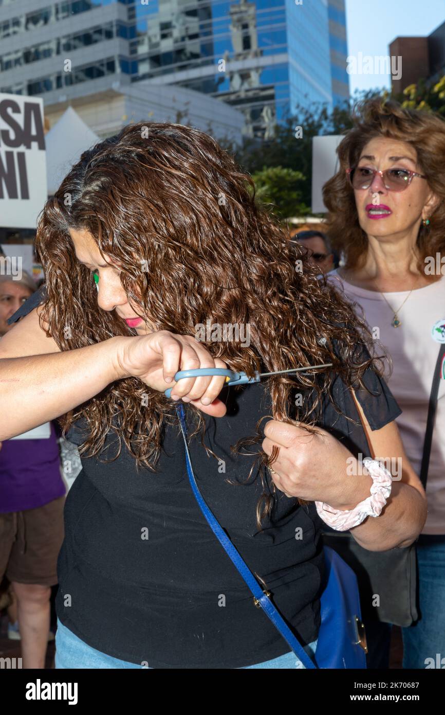 A young woman cuts off a lock of her hair as a sign of solidarity in ...