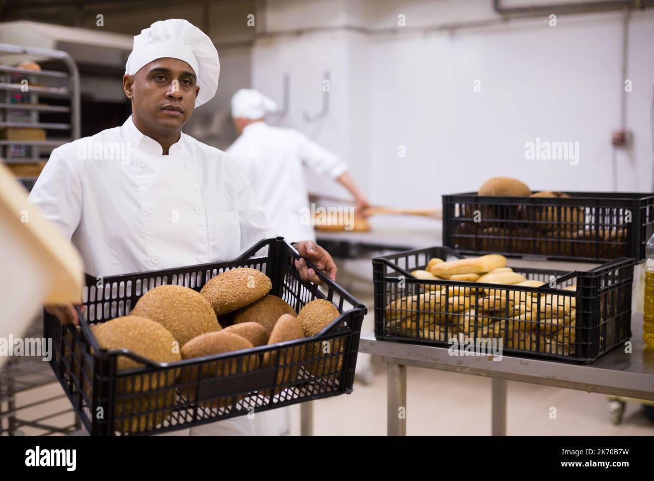Male baker holding crate with baked bread Stock Photo - Alamy