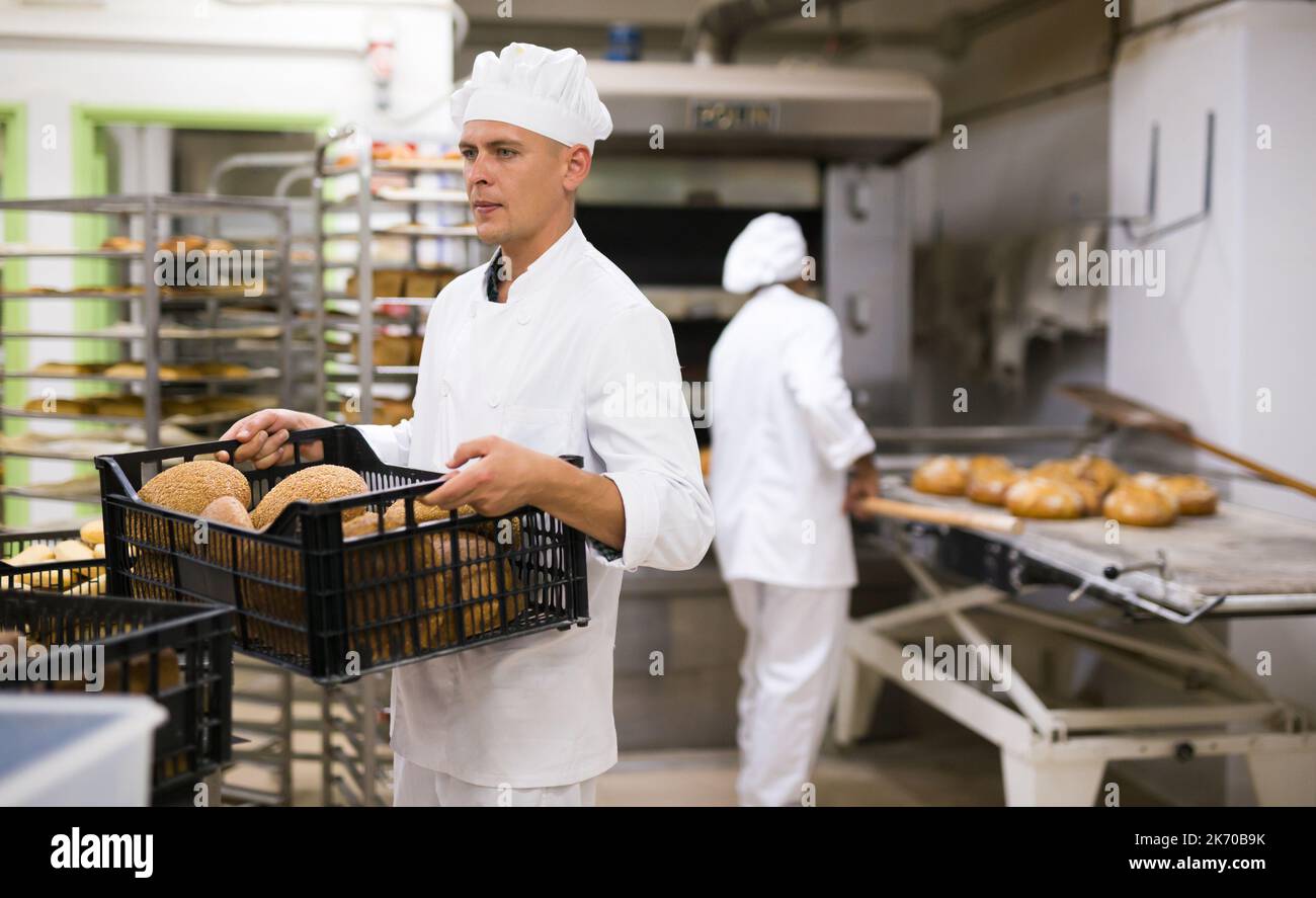 Male baker carrying crate with baked bread Stock Photo - Alamy
