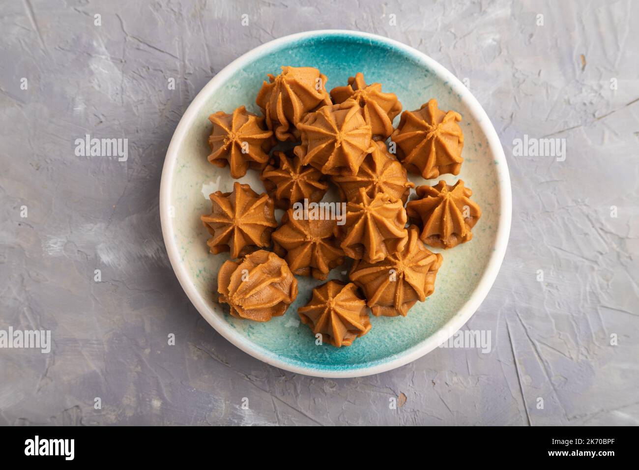 Homemade soft caramel fudge candies on blue plate on gray concrete ...