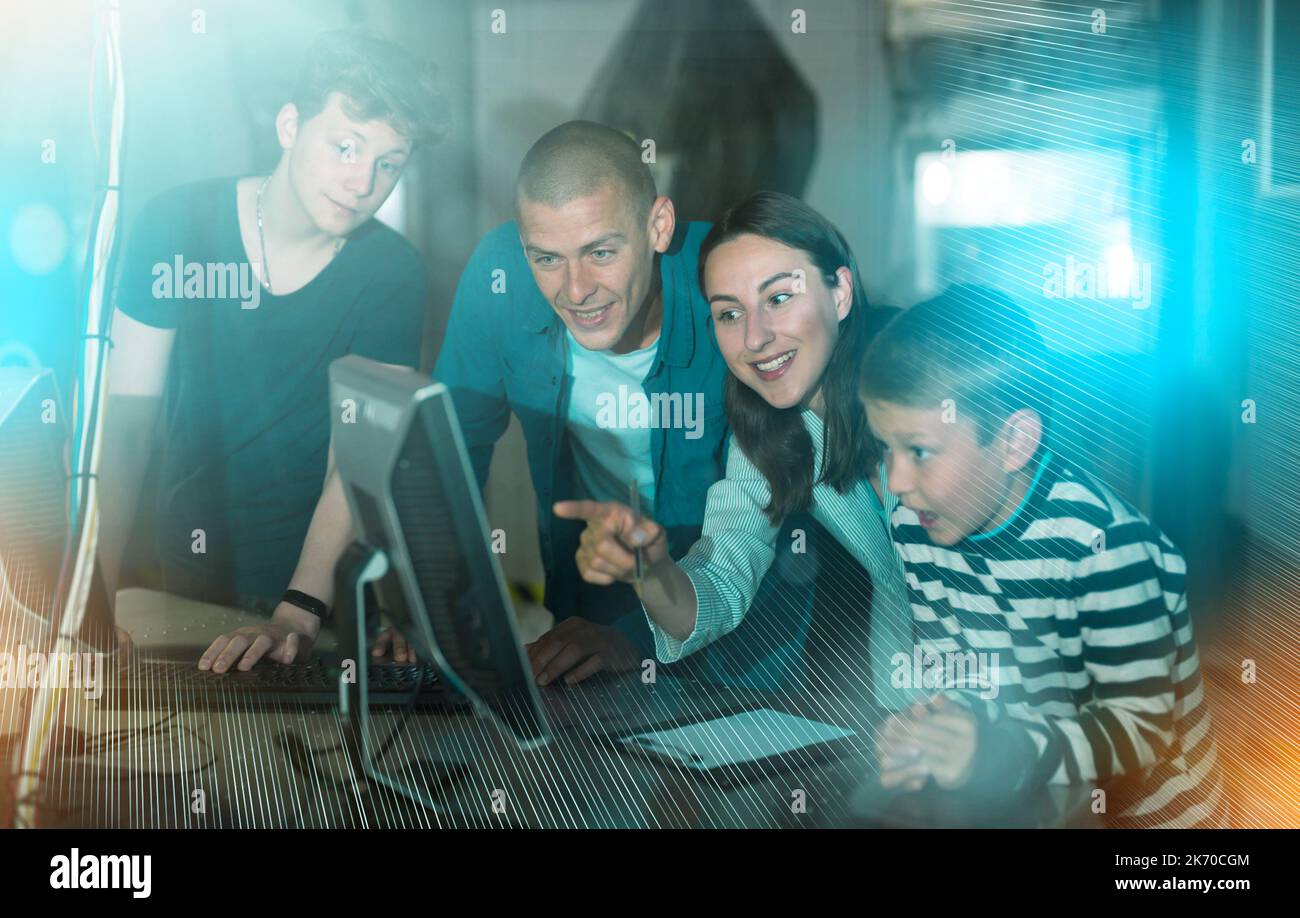 Happy family using computer in closed escape room stylized as bunker ...