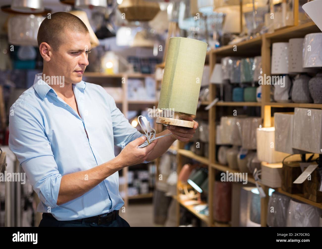 Man choosing table lamps in store Stock Photo - Alamy