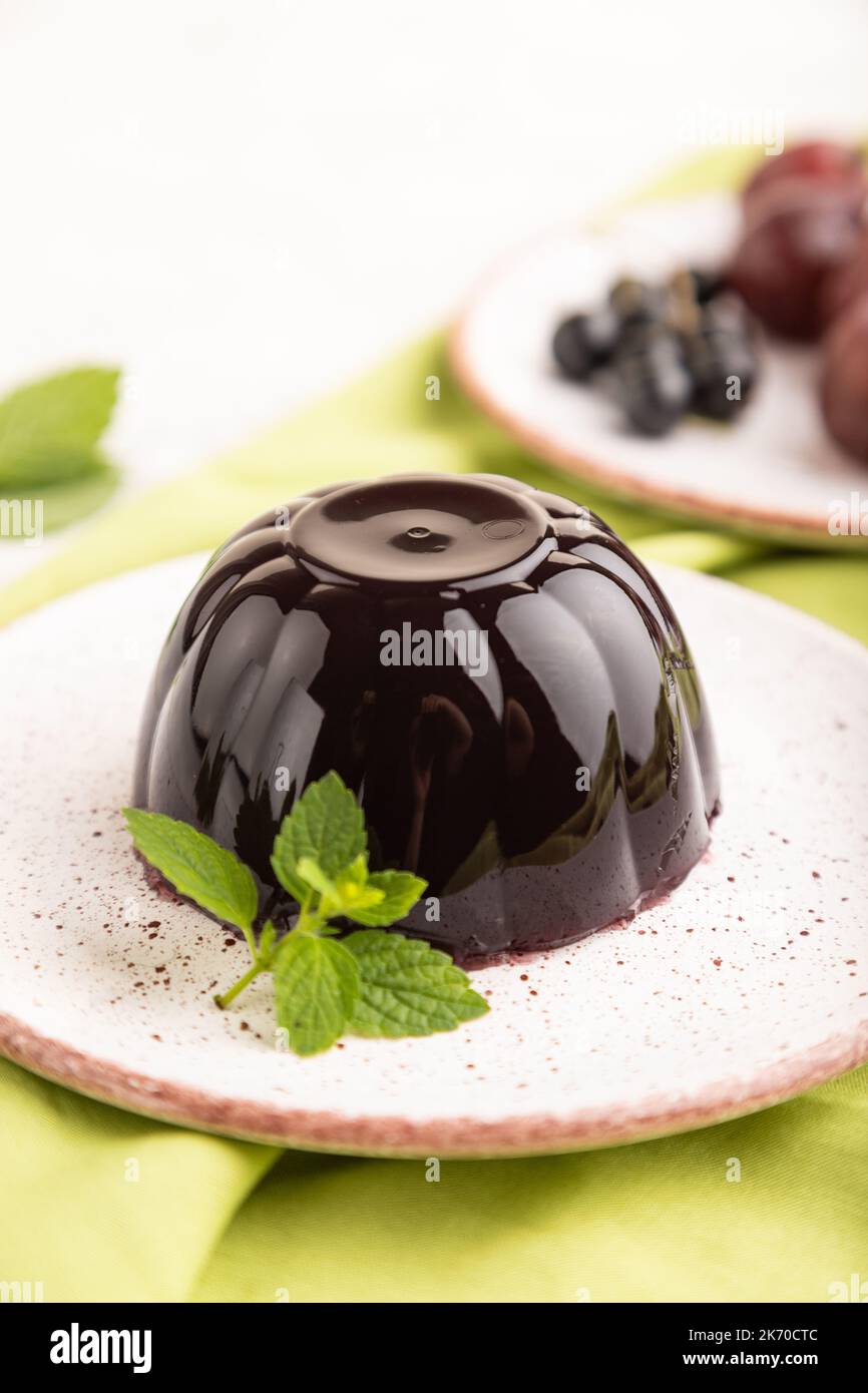 Black currant and grapes jelly on gray concrete background and green ...