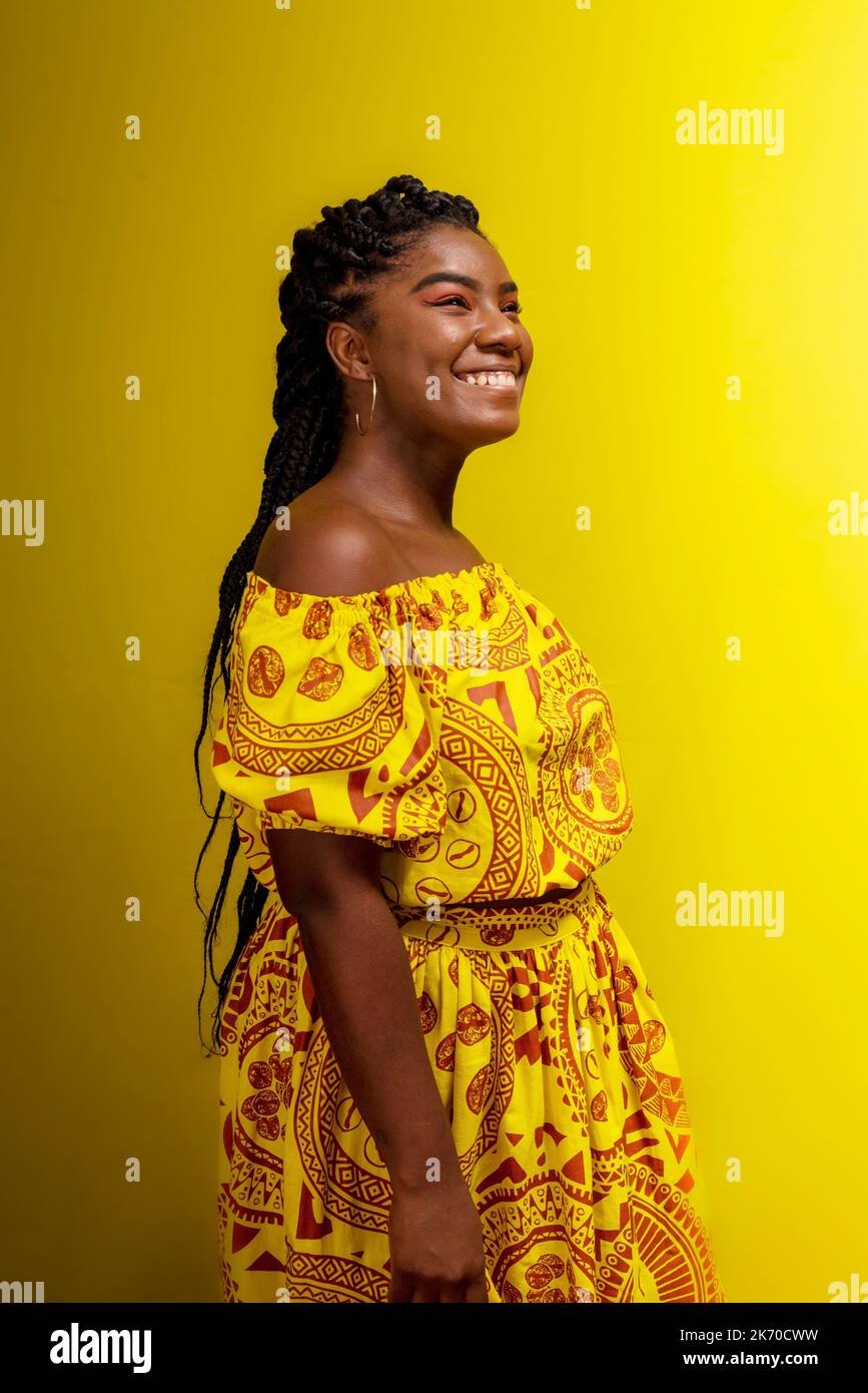 Portrait of happy young African Brazilian woman smiling against yellow ...