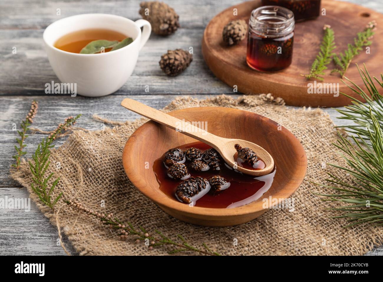 Pine cone jam with herbal tea on gray wooden background and linen ...