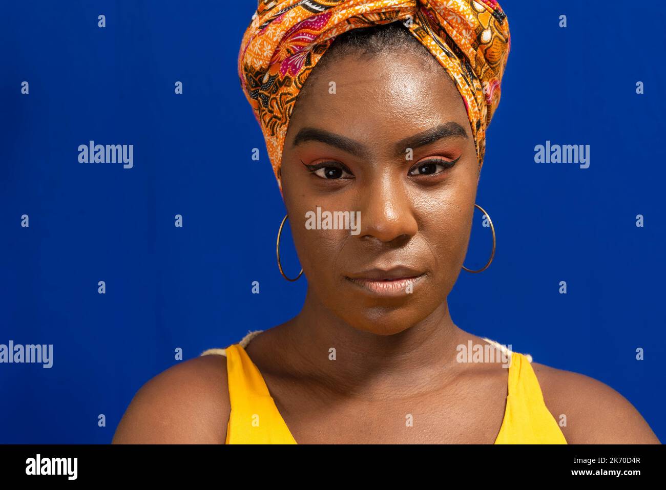 Close-up portrait of an Afro-Brazilian woman against blue background ...