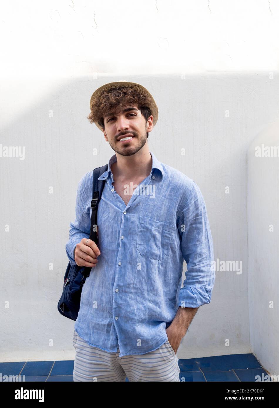 Portrait of a young Italian man with a straw hat looking at the camera ...
