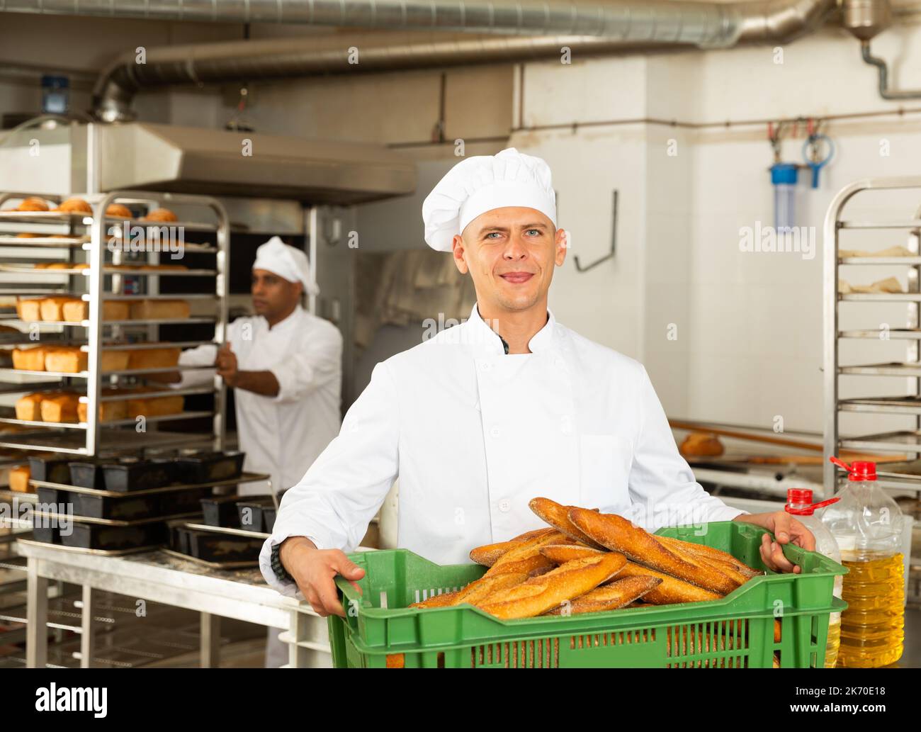 man in chefs uniform with bread in tray in bakery Stock Photo - Alamy
