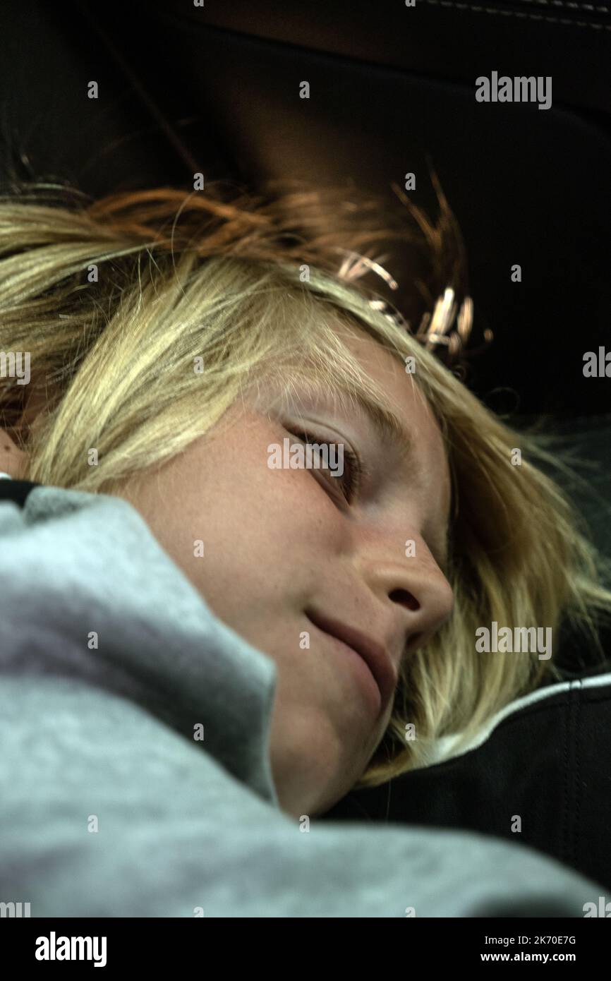 Boy laying down on back seat of car during travel Stock Photo - Alamy