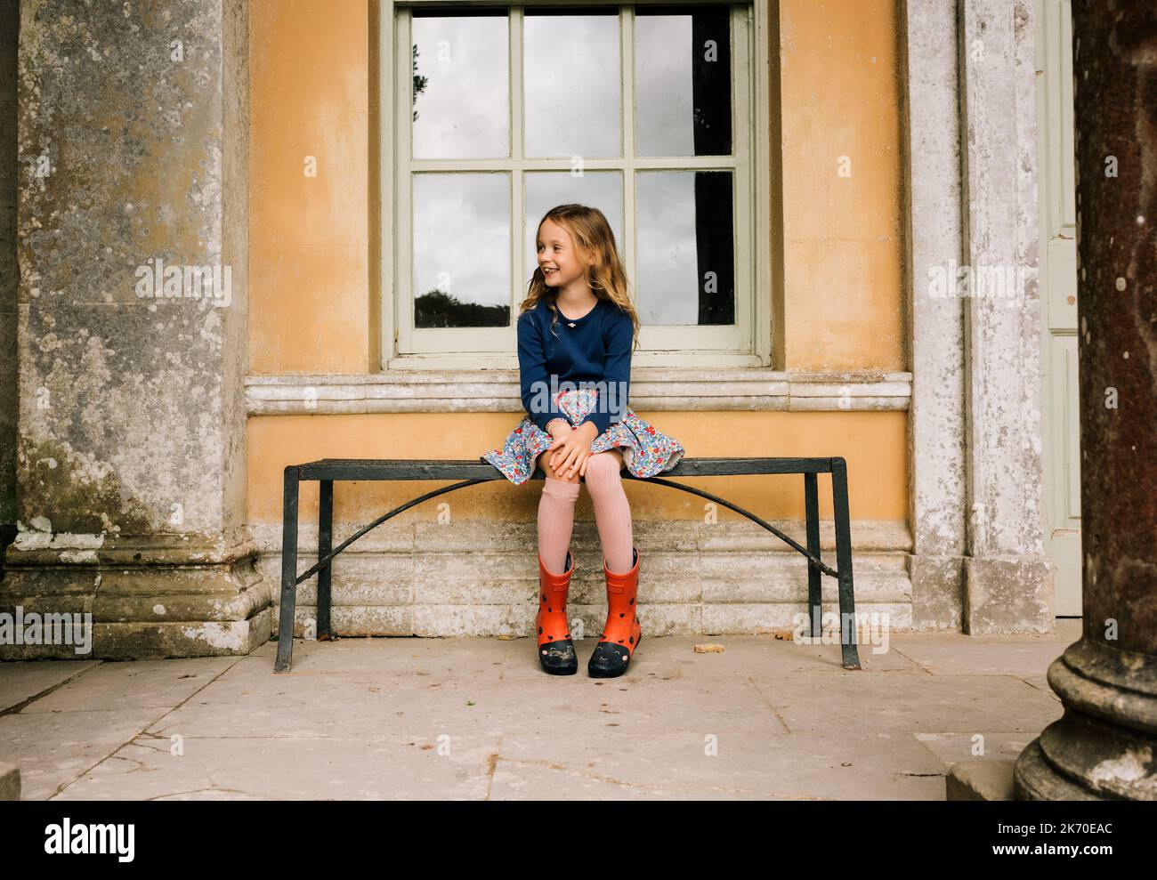 girl sitting happily on a bench outside a castle in England Stock Photo ...
