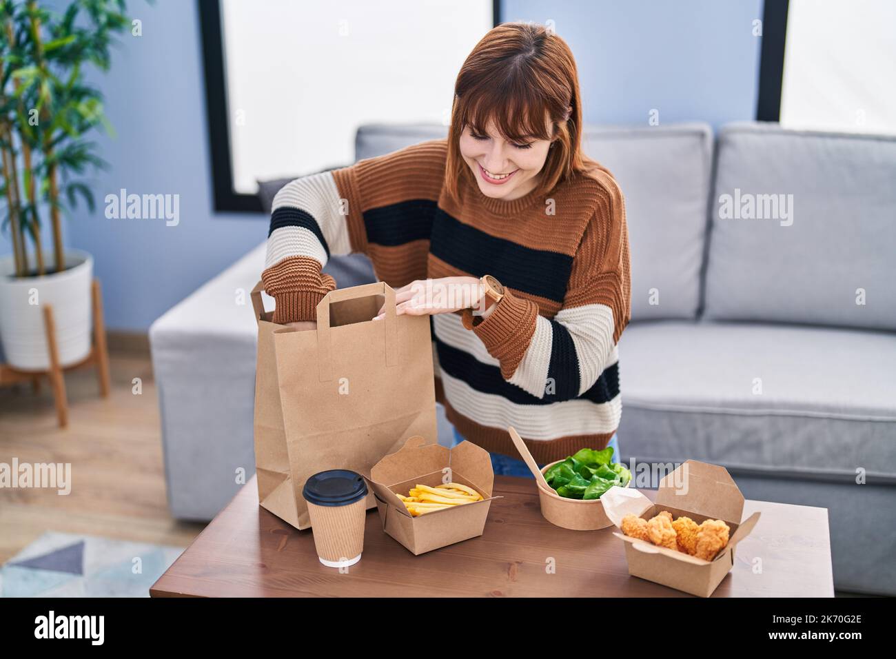 Young woman holding take away food of paper bag at home Stock Photo - Alamy