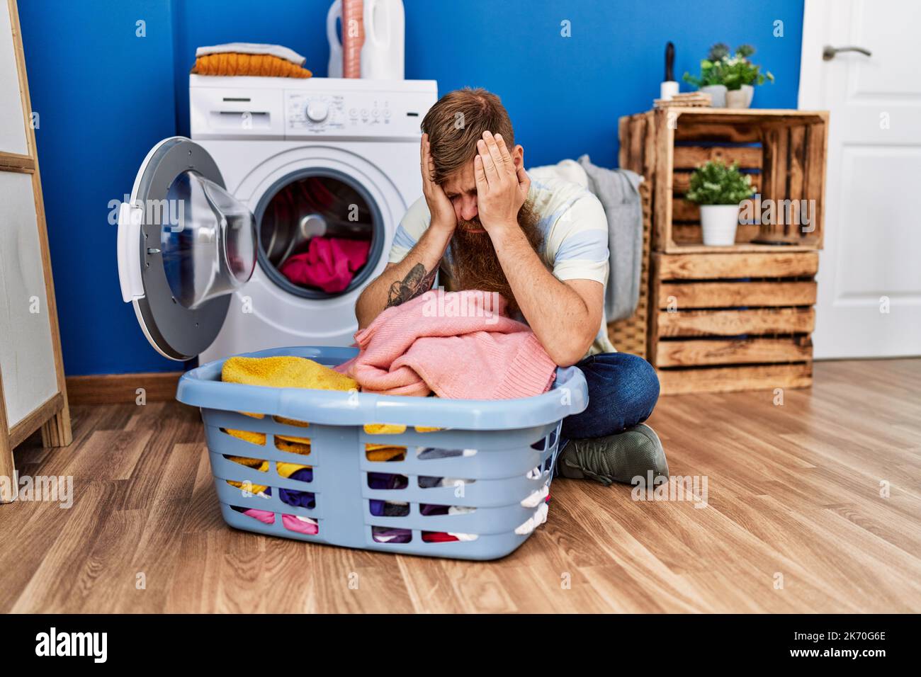 Young redhead man stressed washing clothes at laundry room Stock Photo ...