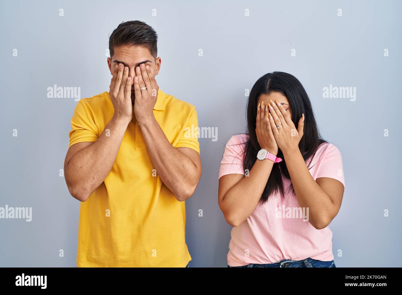 Young couple standing over isolated background rubbing eyes for fatigue ...