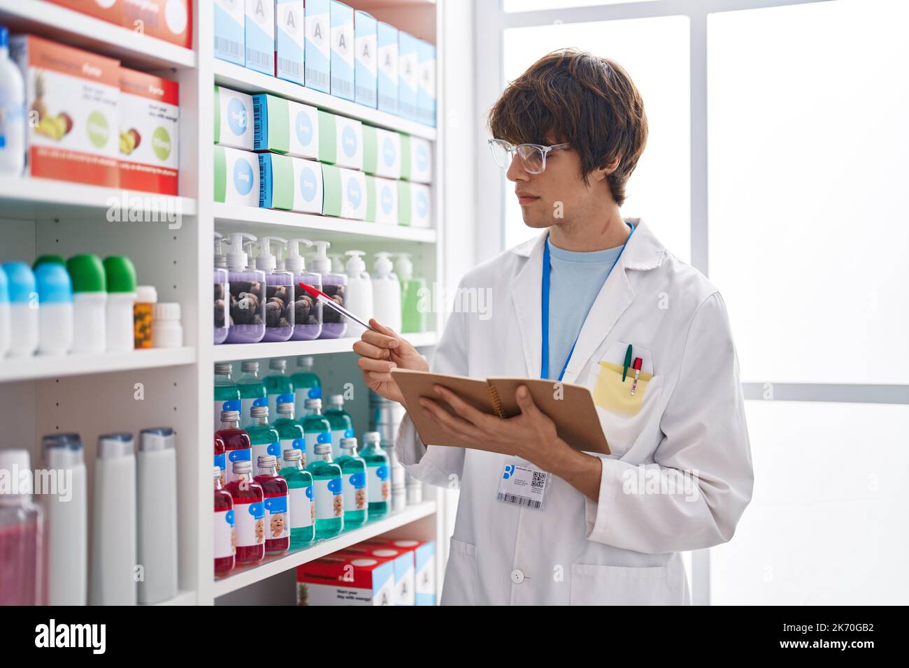 Young blond man pharmacist writing on notebook at pharmacy Stock Photo ...