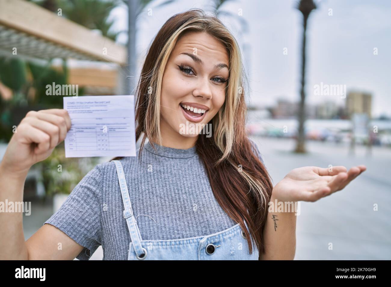 Young caucasian woman holding covid record card celebrating achievement ...