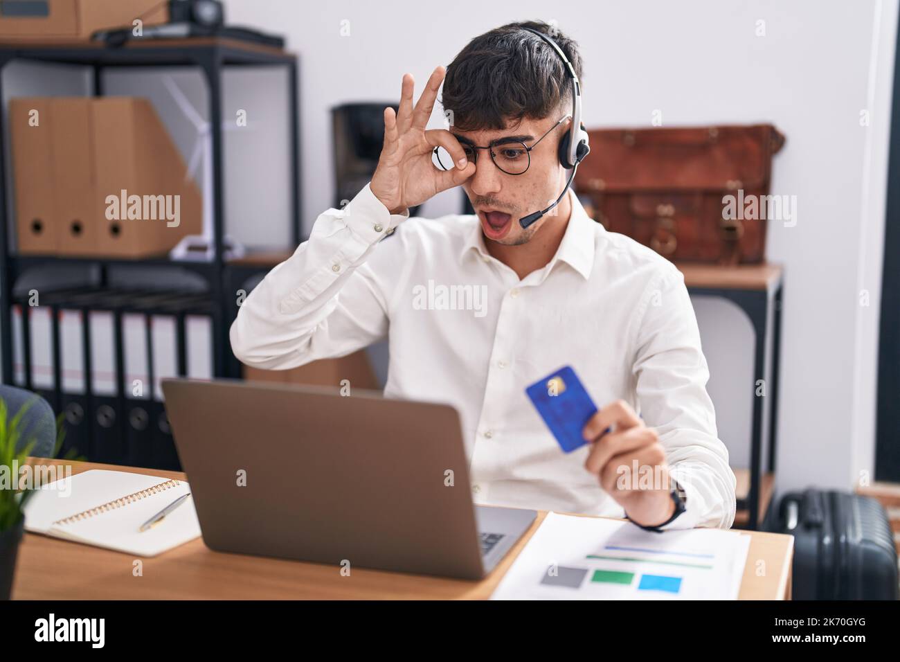 Young hispanic man working using computer laptop holding credit card ...