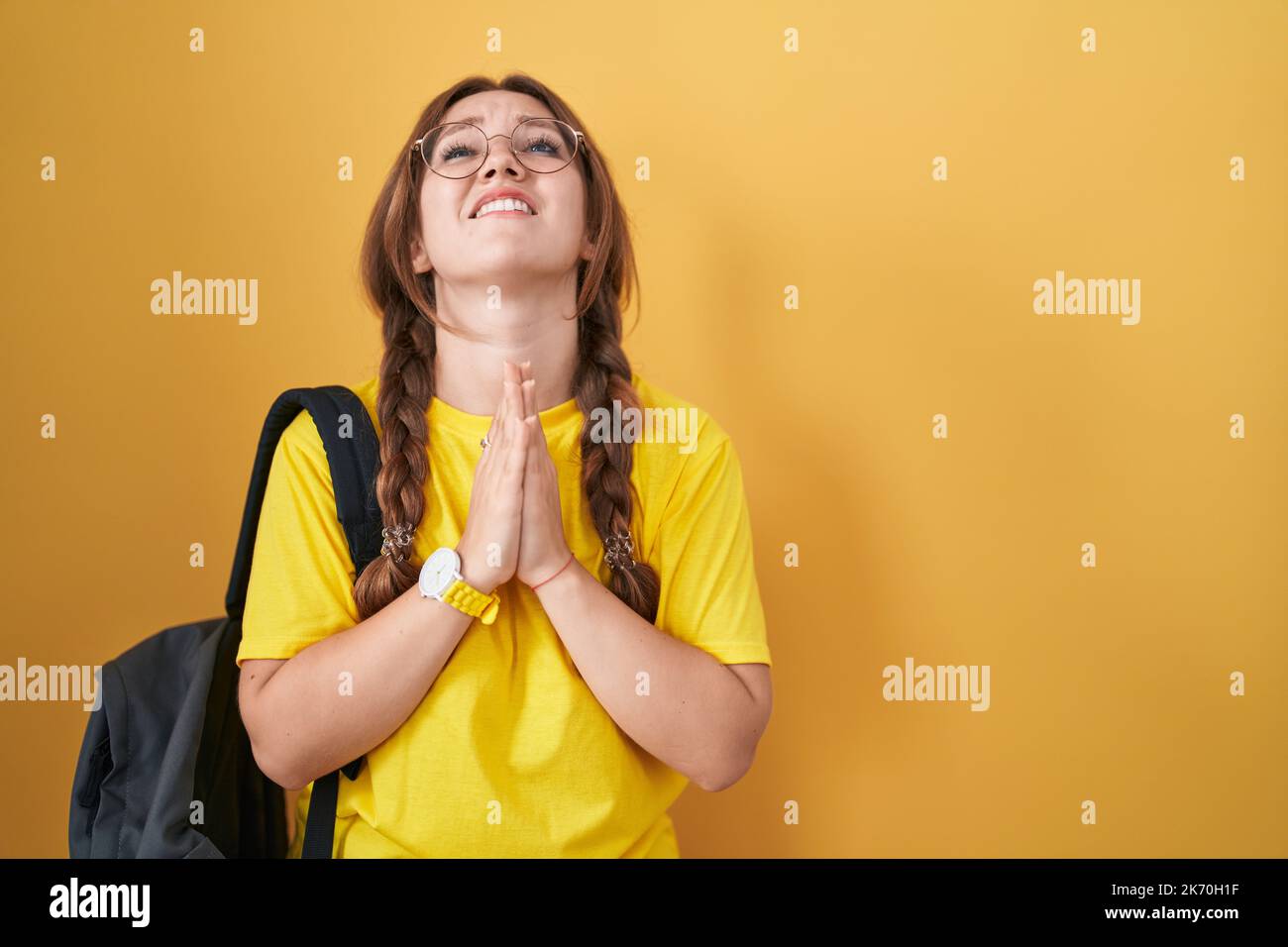 Young caucasian woman wearing student backpack over yellow background ...