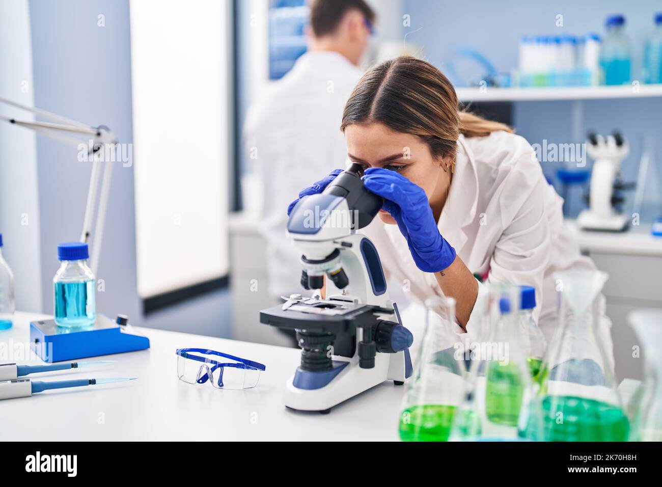 Young man and woman scientists workers using microscope at laboratory ...