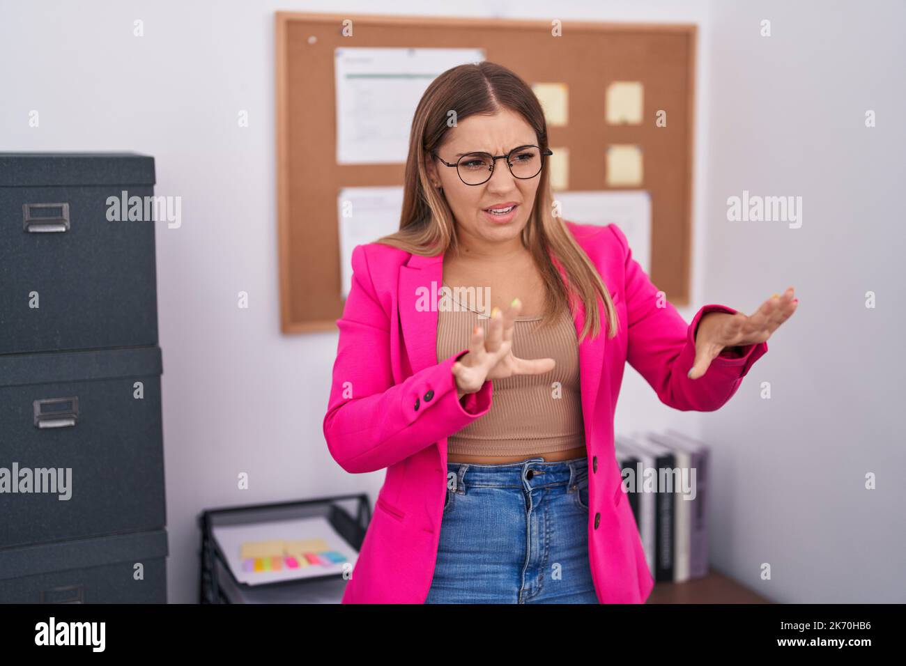 Young blonde woman standing at the office afraid and terrified with ...