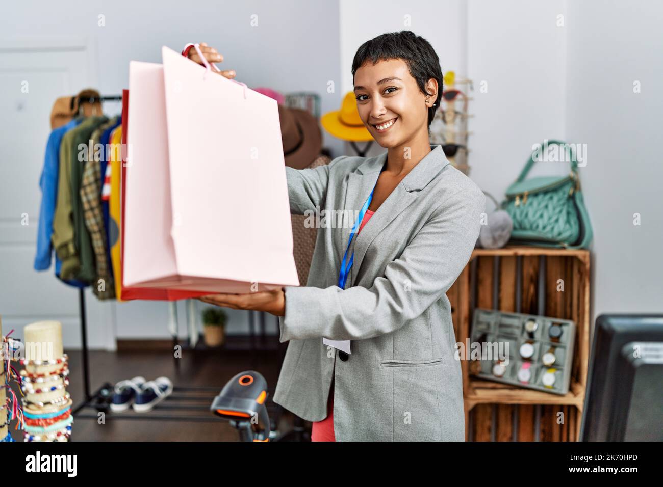 Young hispanic woman shopkeeper smiling confident holding shopping bag ...