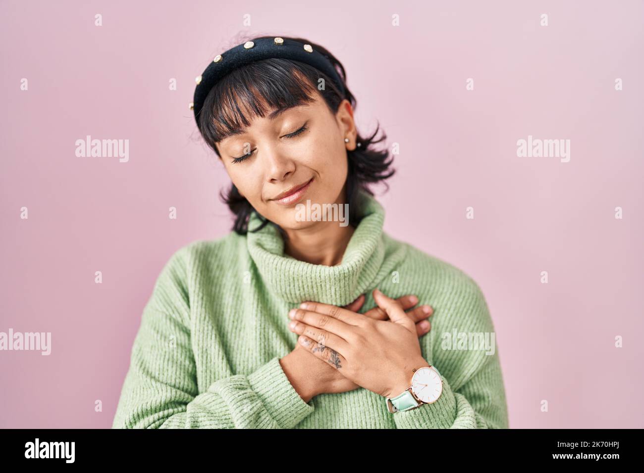Young beautiful woman standing over pink background smiling with hands ...