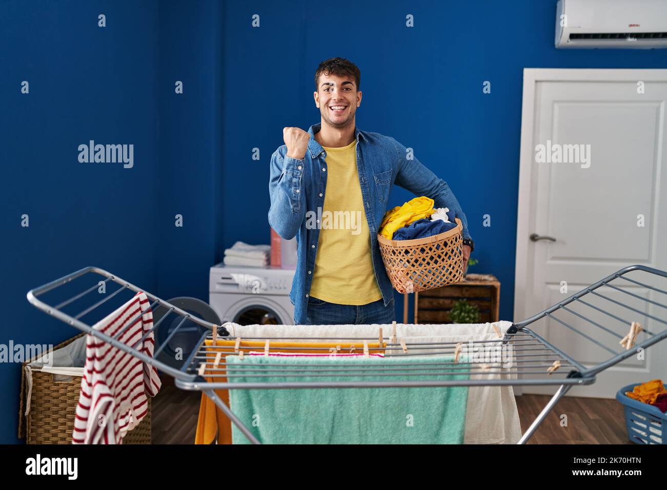 Young hispanic man hanging clothes at clothesline screaming proud ...