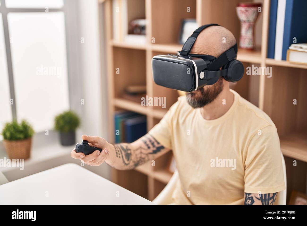 Young bald man playing video game using virtual reality glasses at home ...