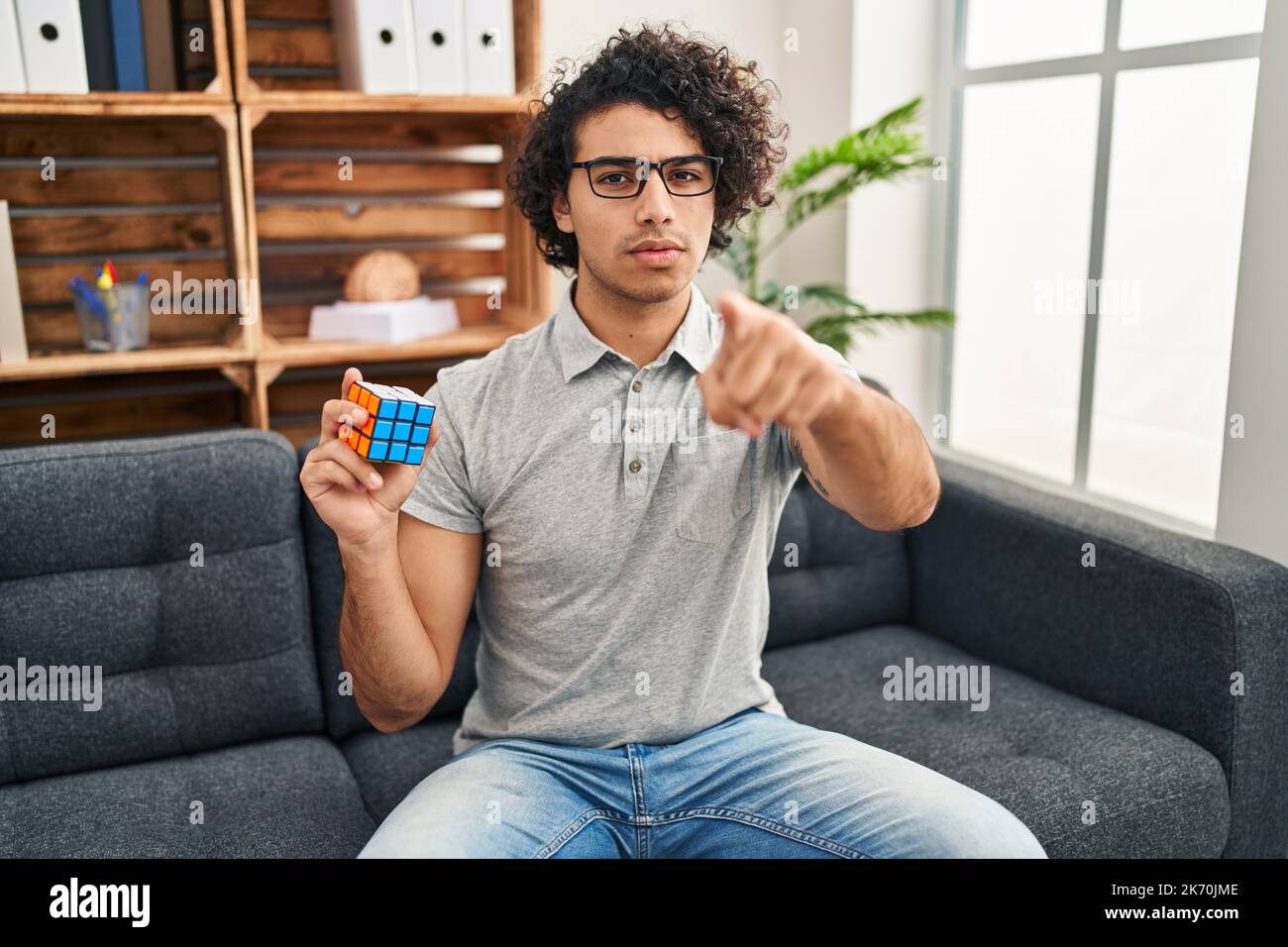 Hispanic man with curly hair playing colorful puzzle cube intelligence ...