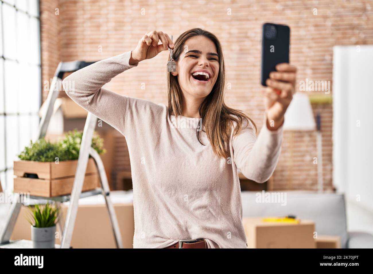 Beautiful woman holding keys of new home showing on video call smiling ...