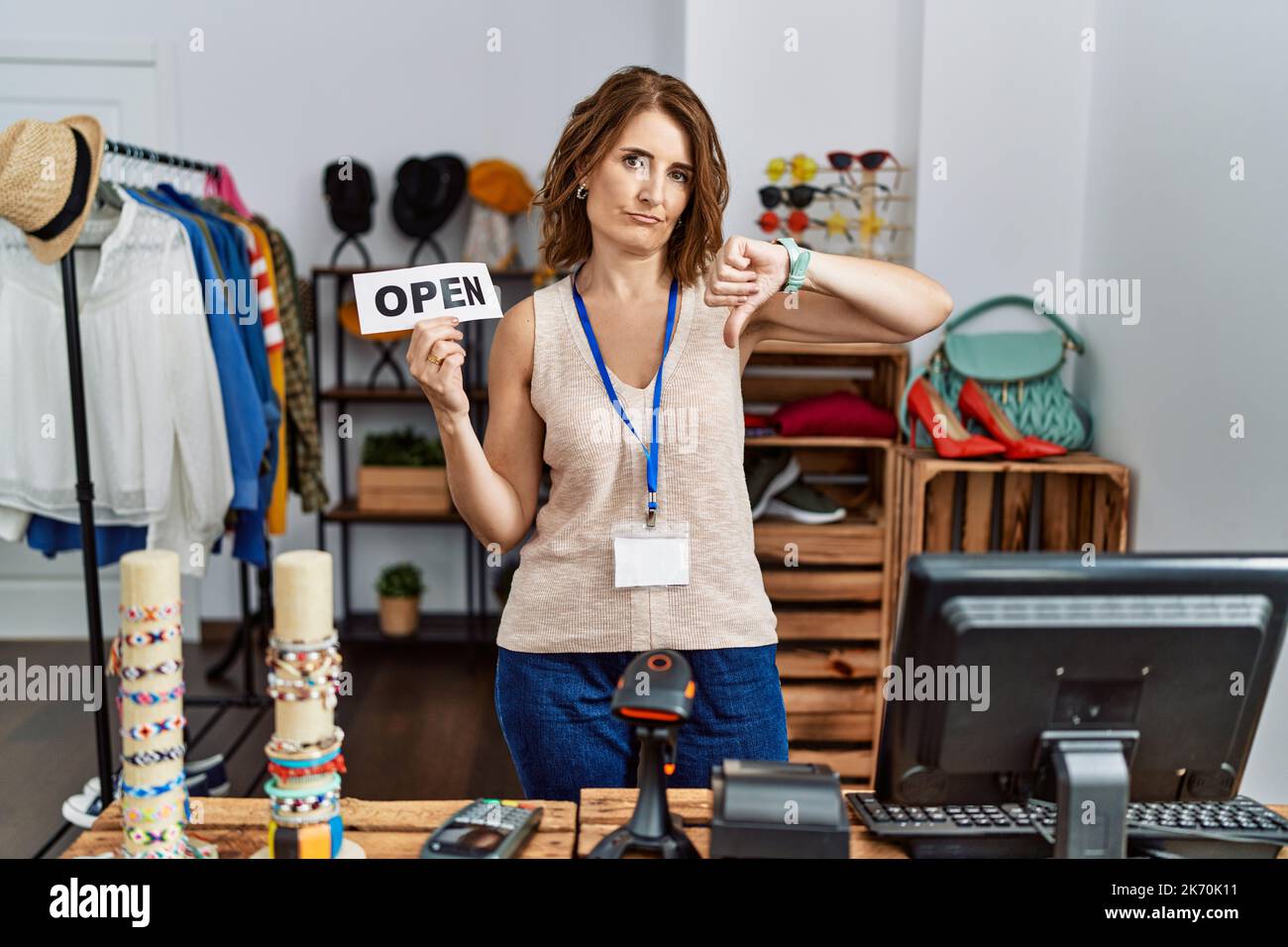 Middle age woman holding banner with open text at retail shop with ...